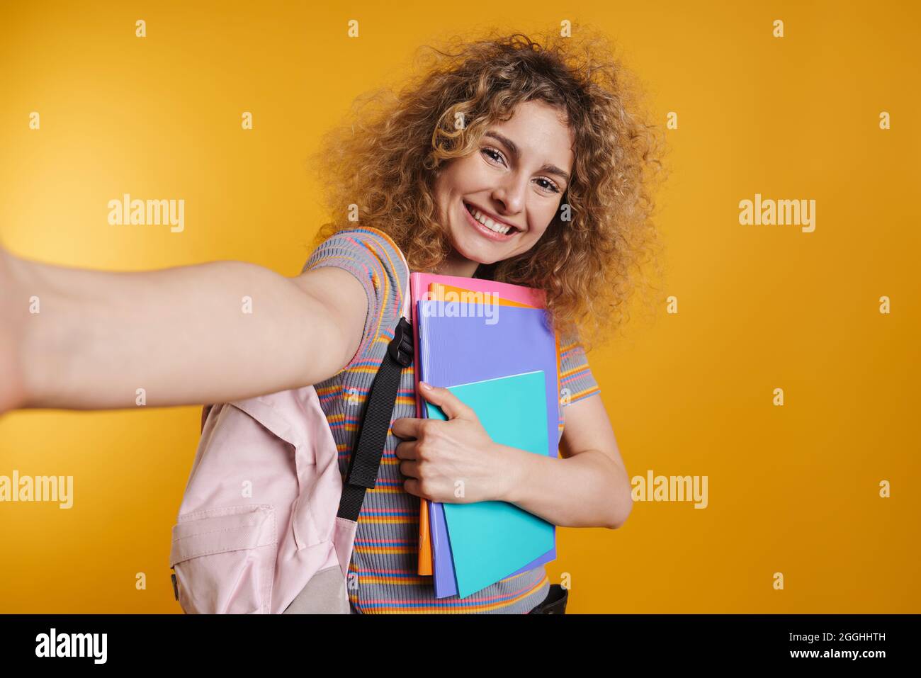 Happy young woman student with backpack standing holding textbooks over ...