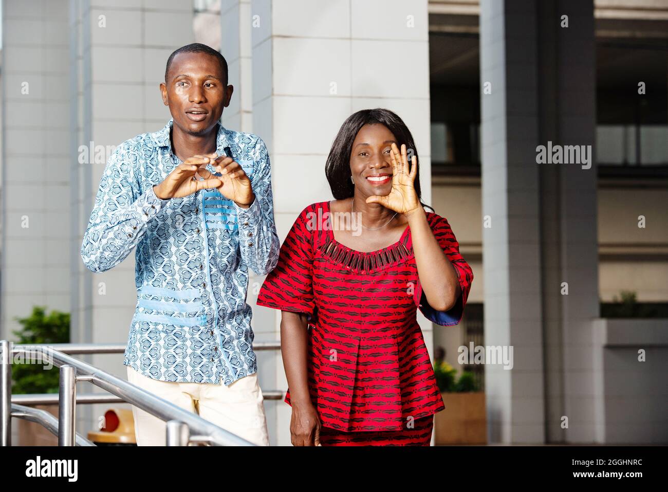 two business people standing in traditional clothes beckoning to ...