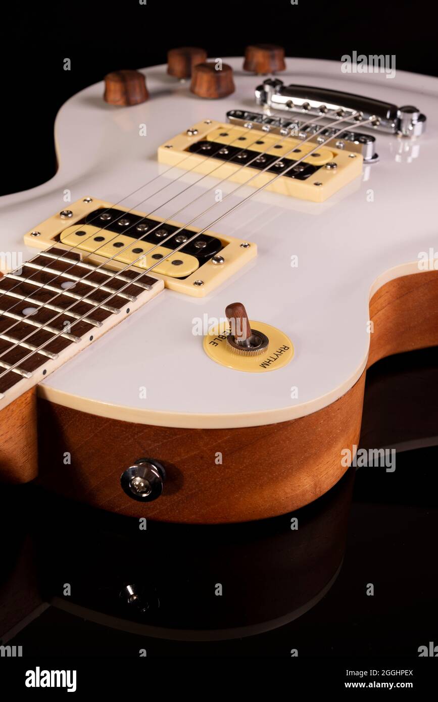 front part of the body of a white electric guitar on black background ...