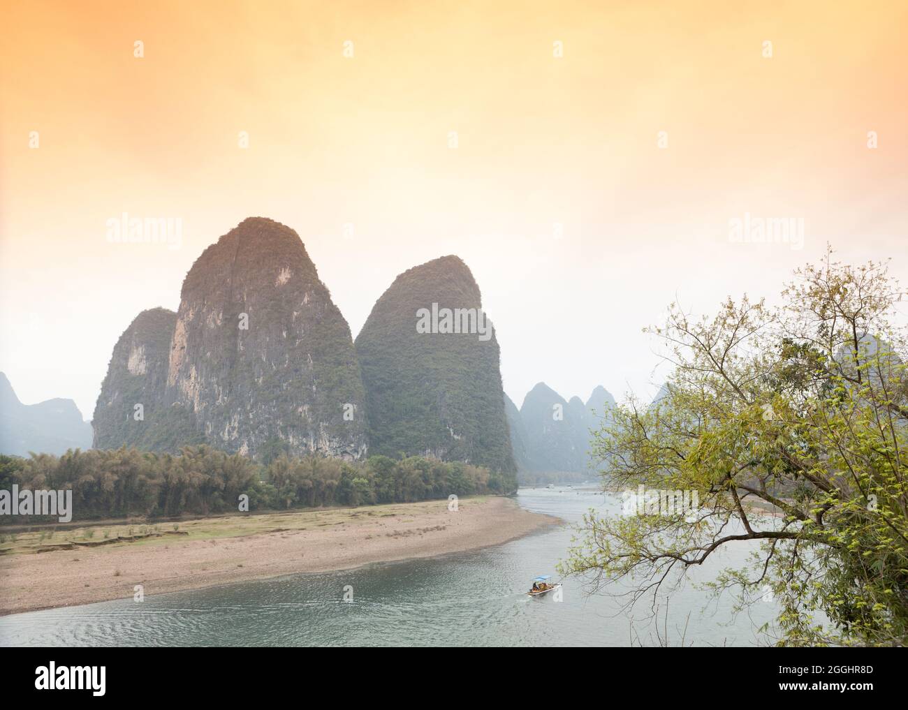 Boats pass below the limestone karst formations along the Li River that ...