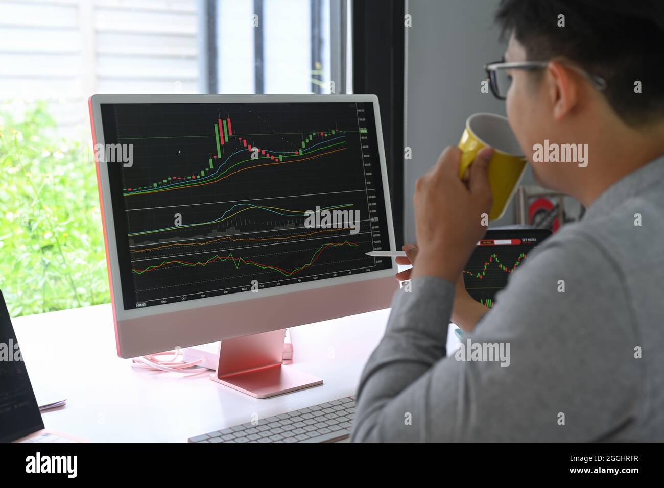 Businessman drinking coffee and checking stock market on desktop ...