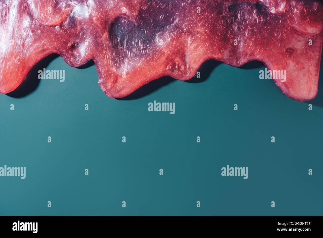Red liquid slime flowing over cyan background Stock Photo - Alamy