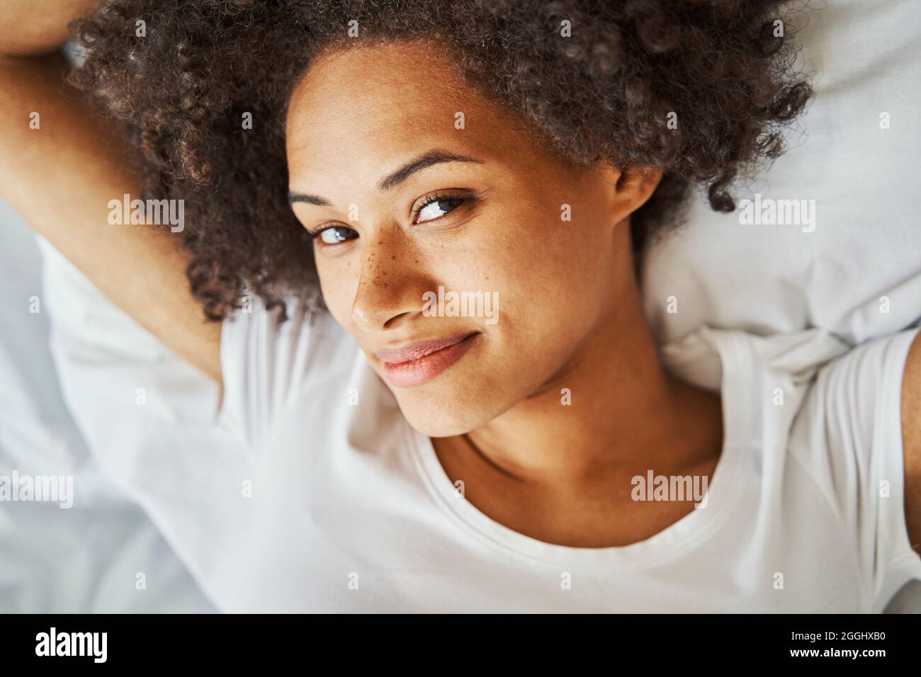 Female with curly hair whiling away the time in bed Stock Photo - Alamy