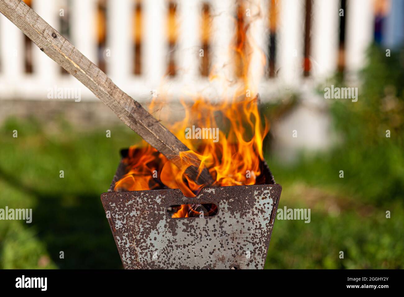 The firewood in the grill burns with a bright orange flame of fire on a ...
