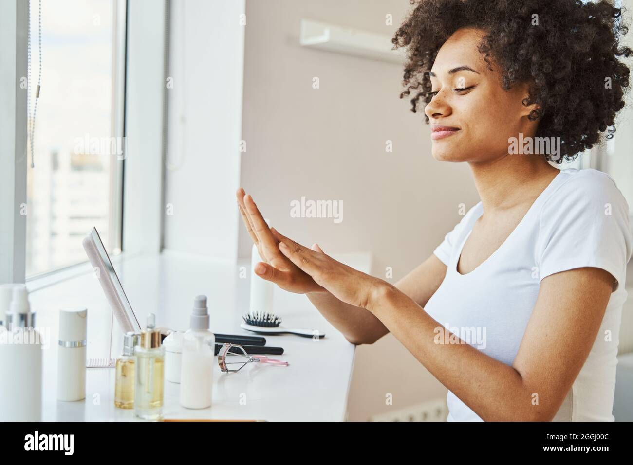 Side view of an attractive serene curly-haired young woman examining ...