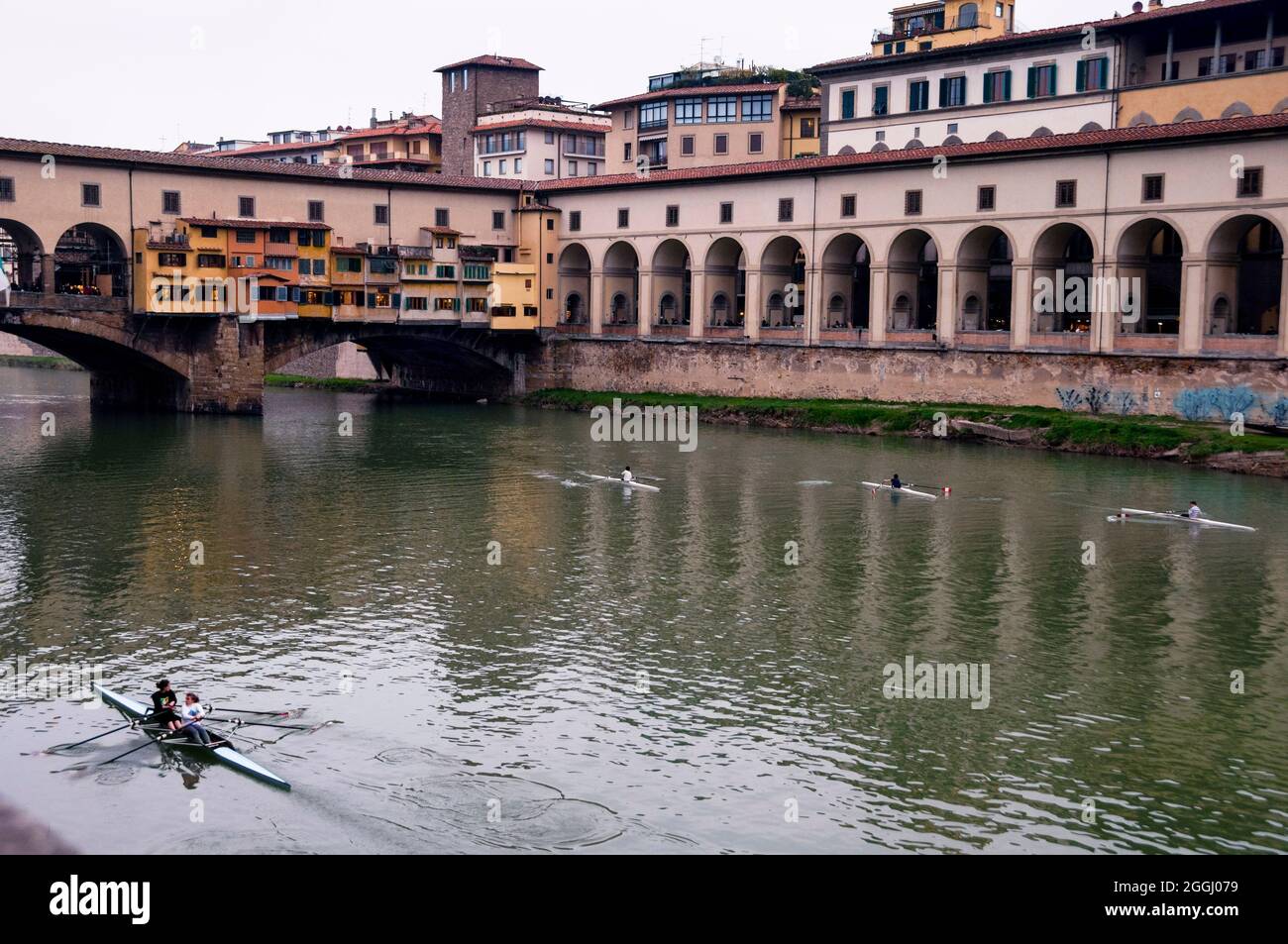 Rowers on the Arno River in Florence passing the Vasari Corridor under ...