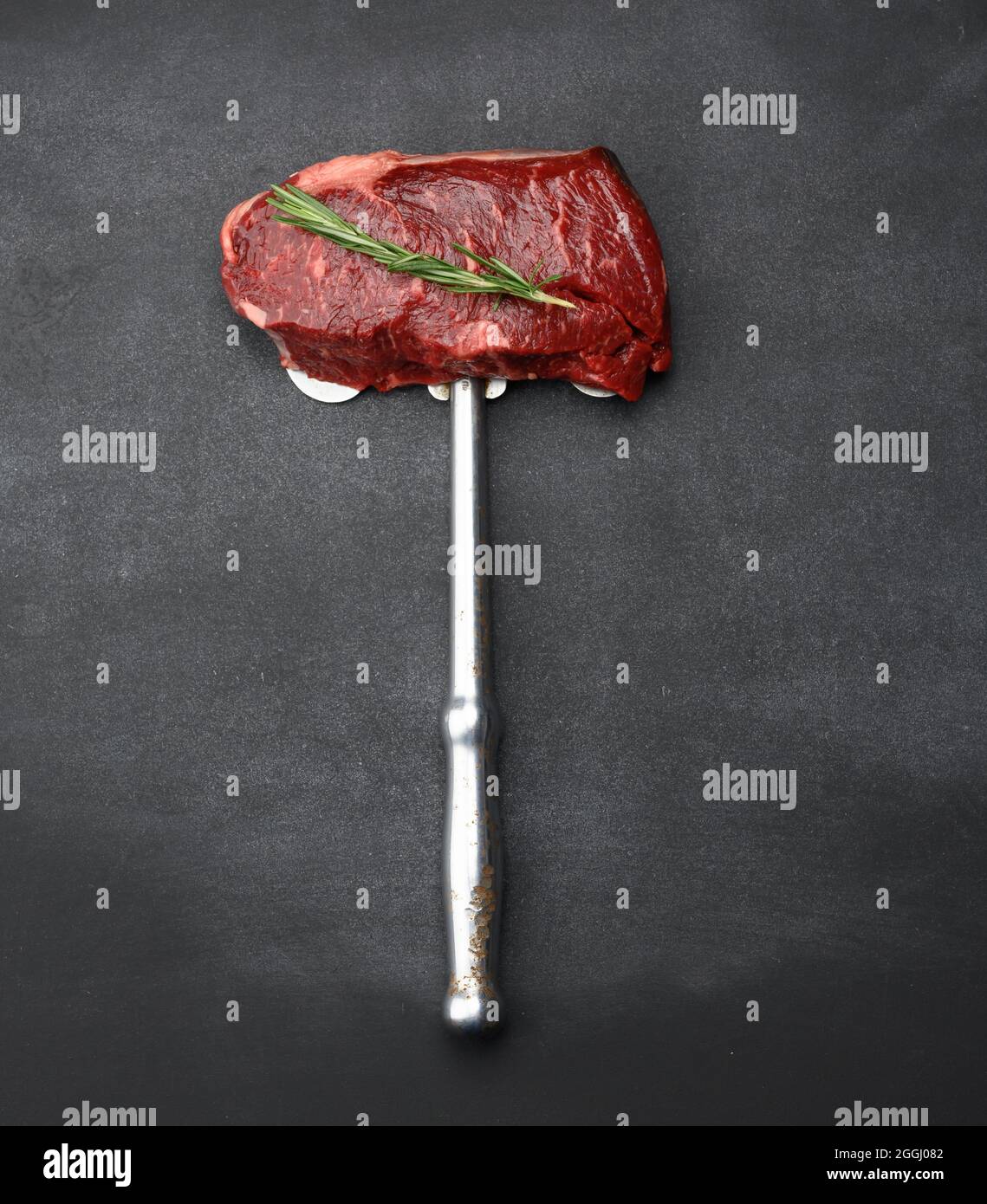 raw piece of beef steak lie on an iron knife, black background. Classic ...