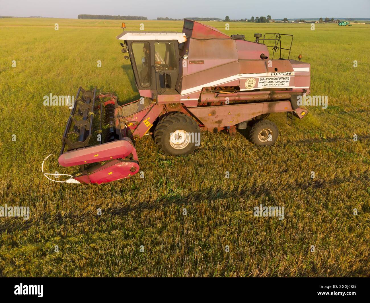 Combine working on the large agricultural field Stock Photo - Alamy