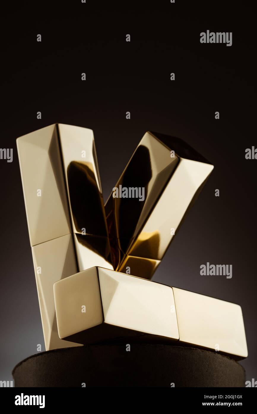 3D rendering of three golden prisms forming the letter K on a black ...