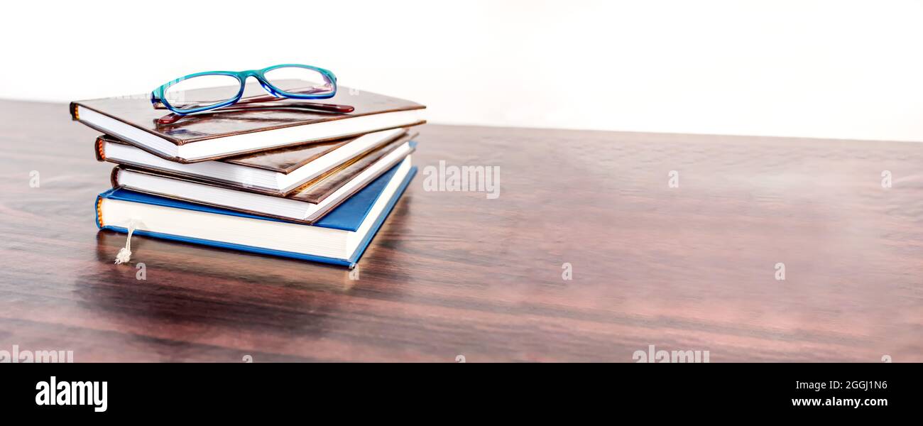 Stack of books with reading glasses on a wooden desk Stock Photo - Alamy