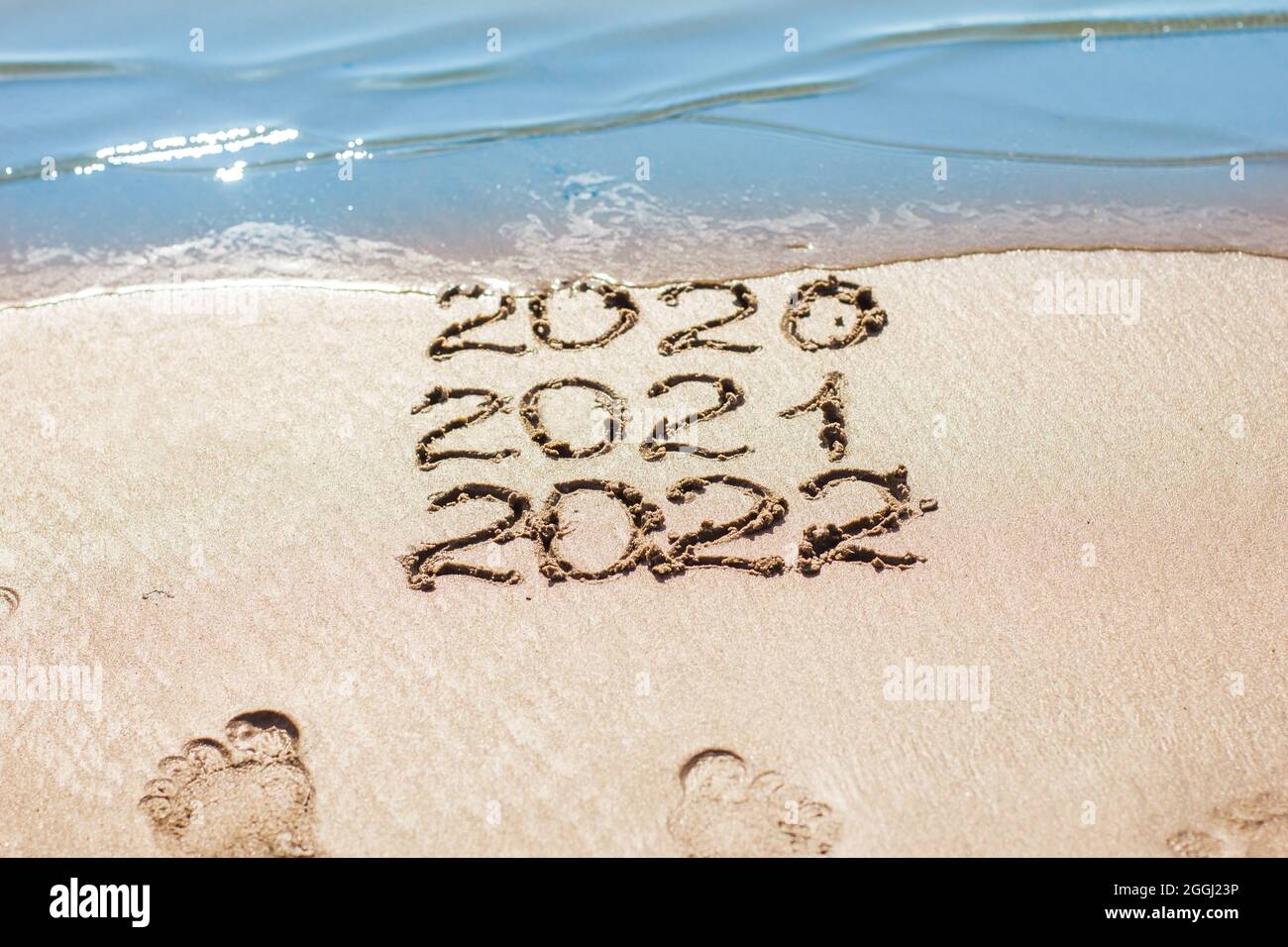 The numbers 2021, 2022 are drawn on the sand and washed away by the ...