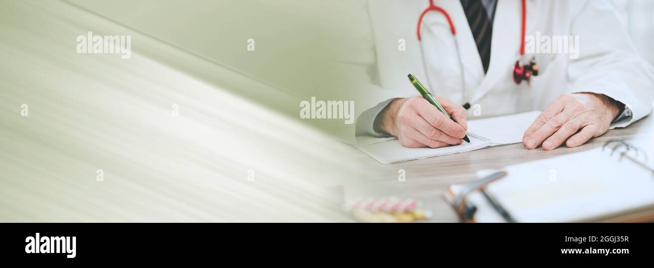 Doctor sitting at desk and taking notes; panoramic banner Stock Photo ...