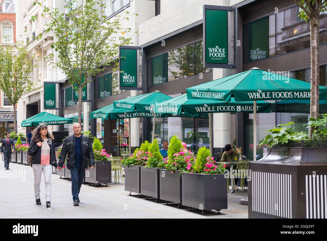 A couple stroll hand-in-hand past the outdoor pavement dining area at ...