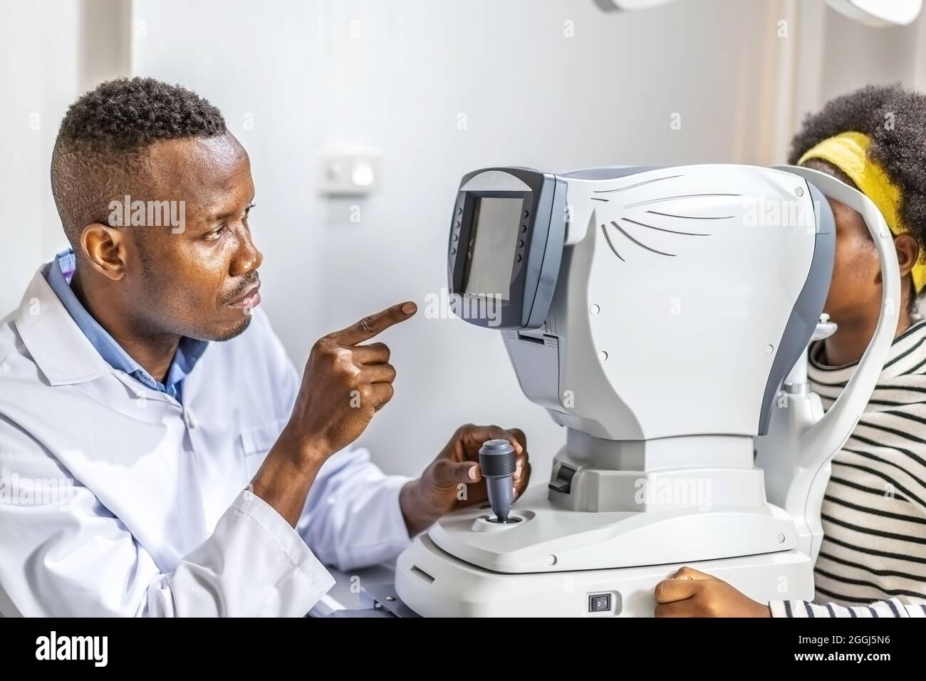 Male doctor ophthalmologist is checking the eye vision of african ...