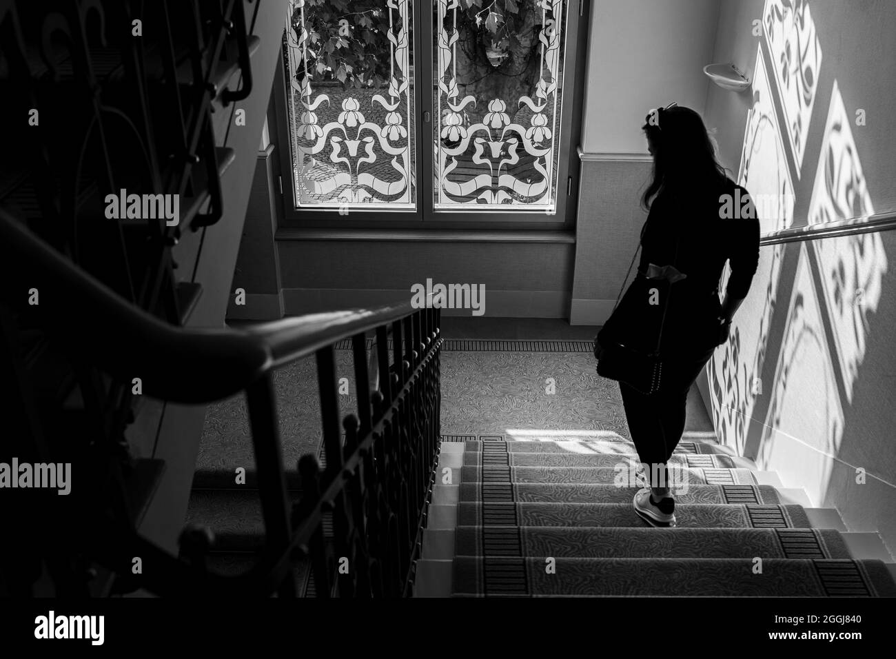 Grayscale shot of a female going downstairs in a decorative building ...