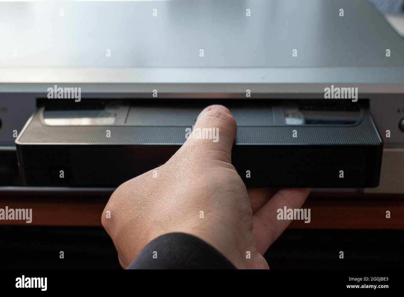 Person inserting an old VHS video cassette tape in a video recorder ...