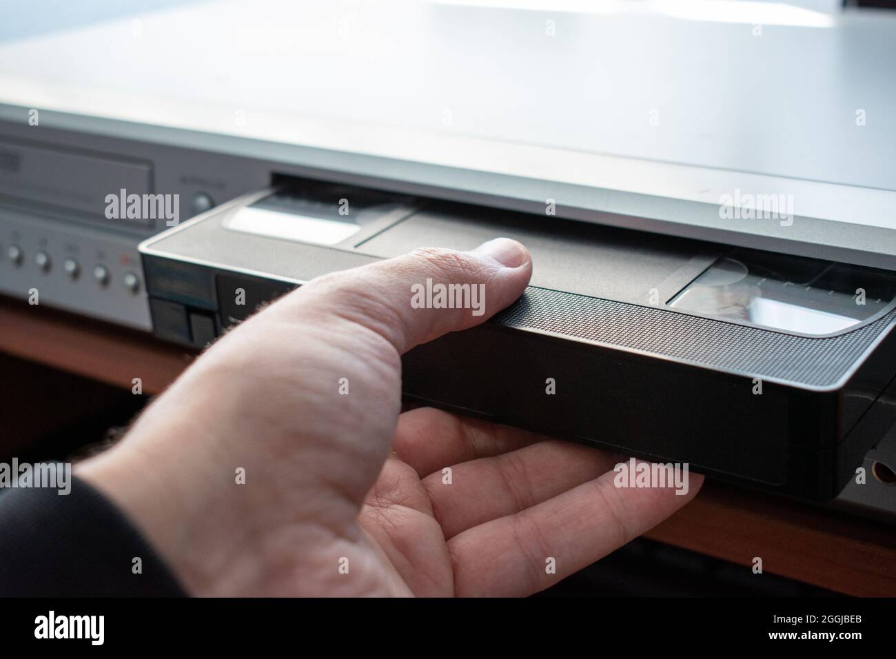 Person inserting an old VHS video cassette tape in a video recorder ...