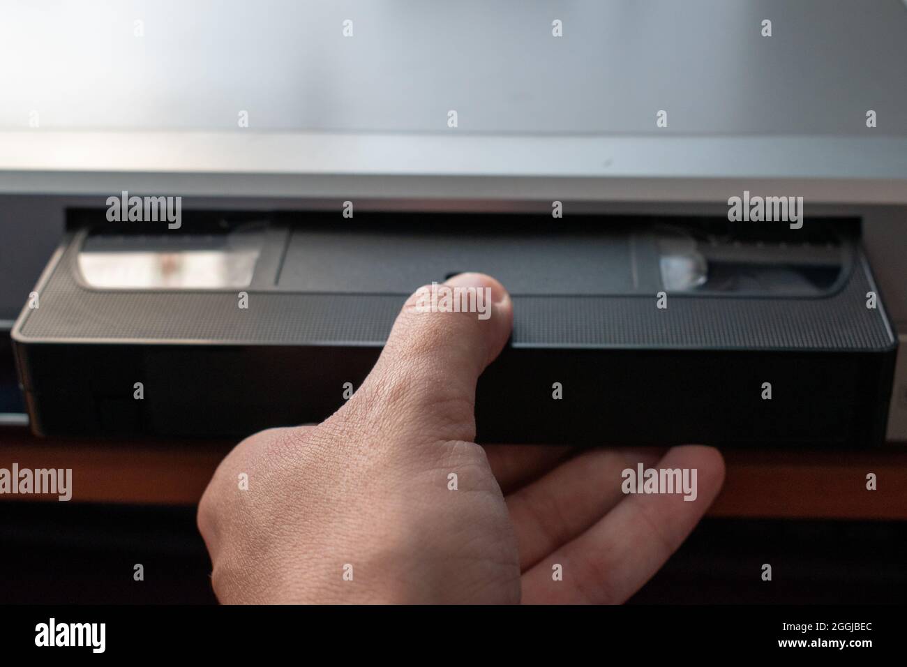 Person inserting an old VHS video cassette tape in a video recorder ...