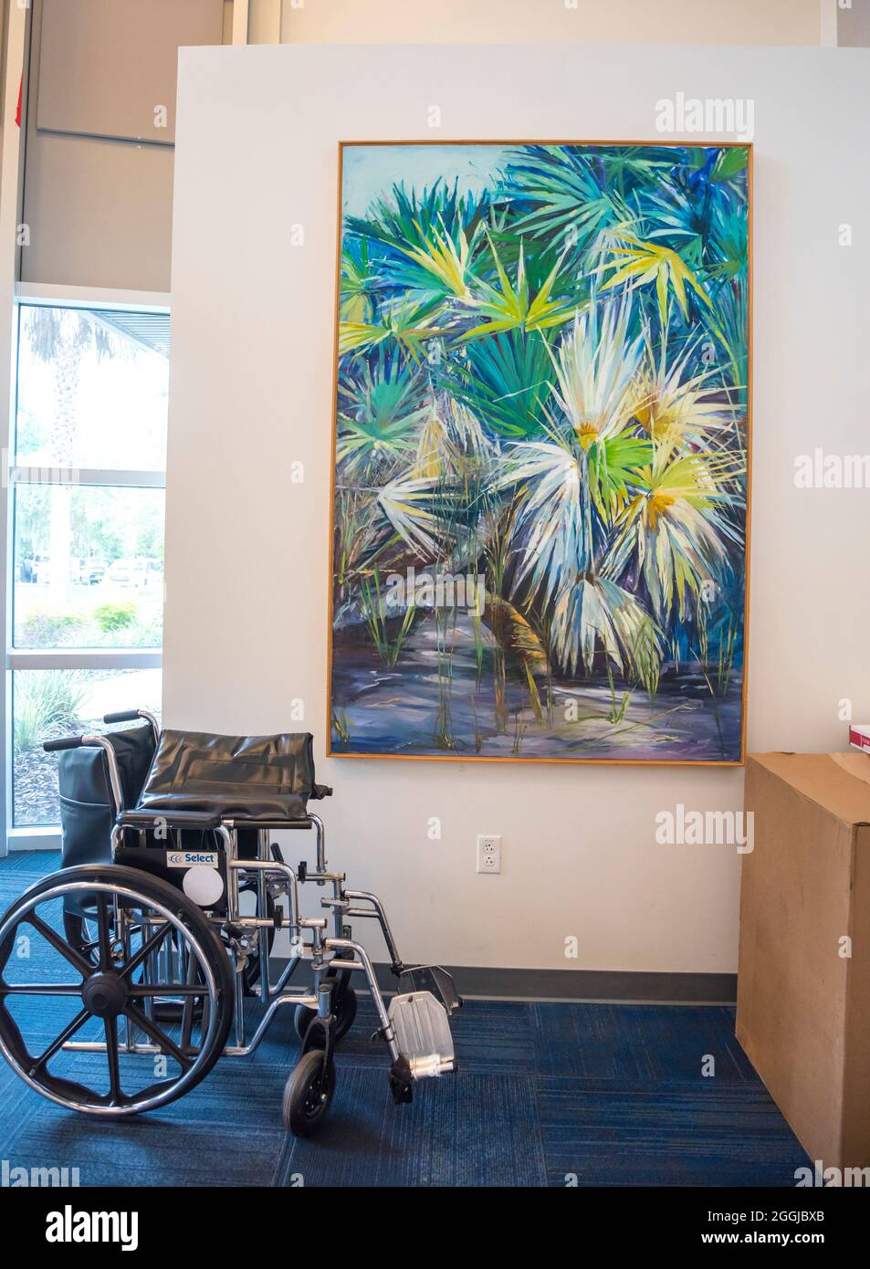 Wheelchair sits by a large painting of palm trees in a medical facility ...