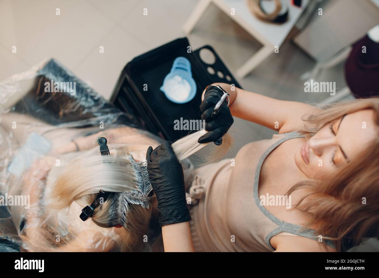 Young woman hairdresser dying hair at beauty salon. Professional hair ...