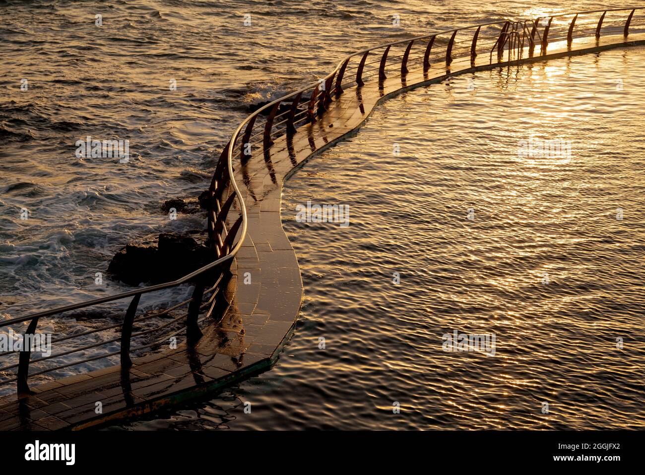 Curved walkway on the water surface under the sunset Stock Photo - Alamy