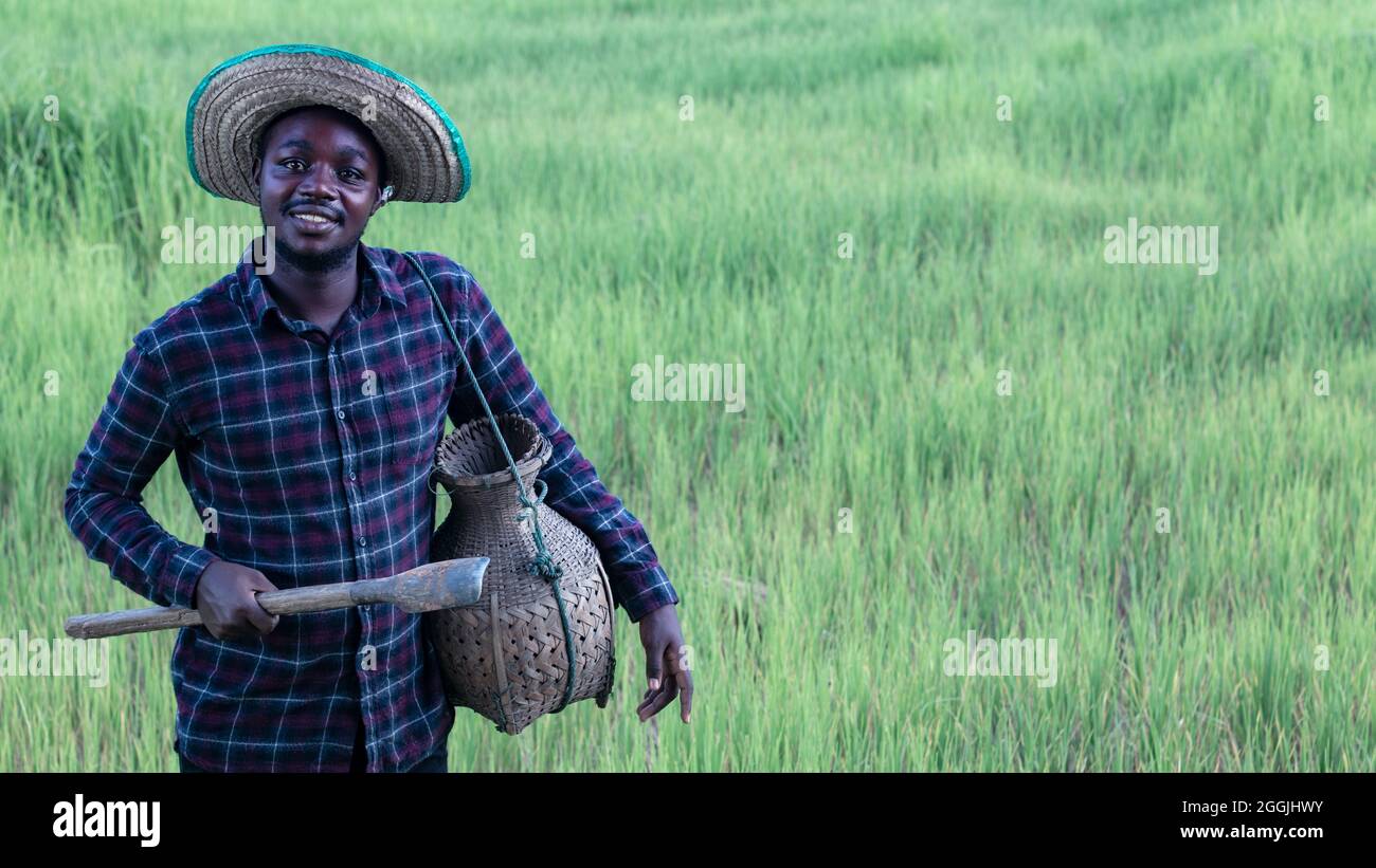 African farmer is happily working on his farm with holding agricultural ...
