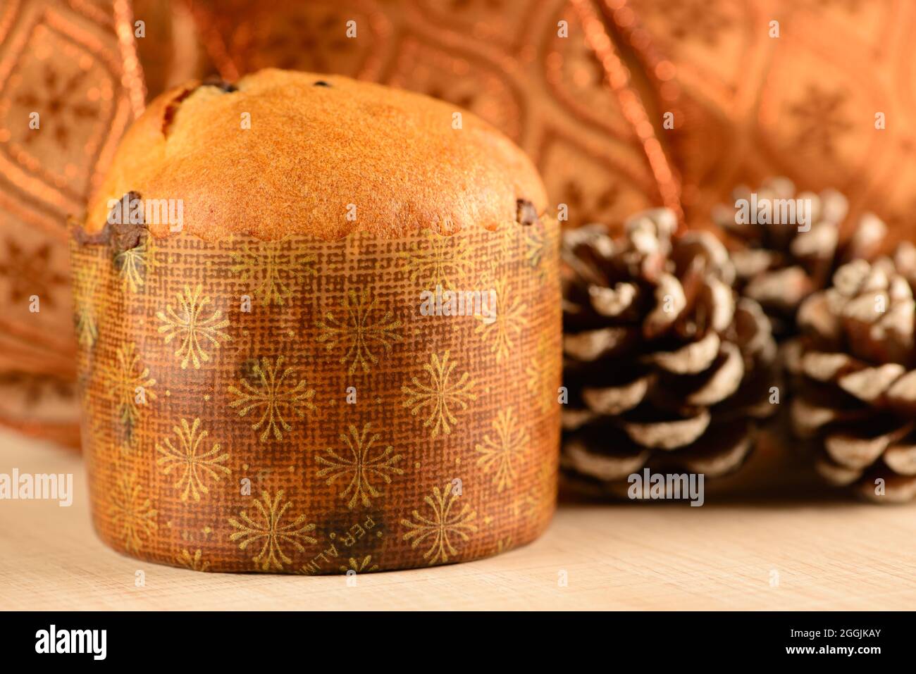 small panettone next to pine cones and decorative ribbon with dark ...