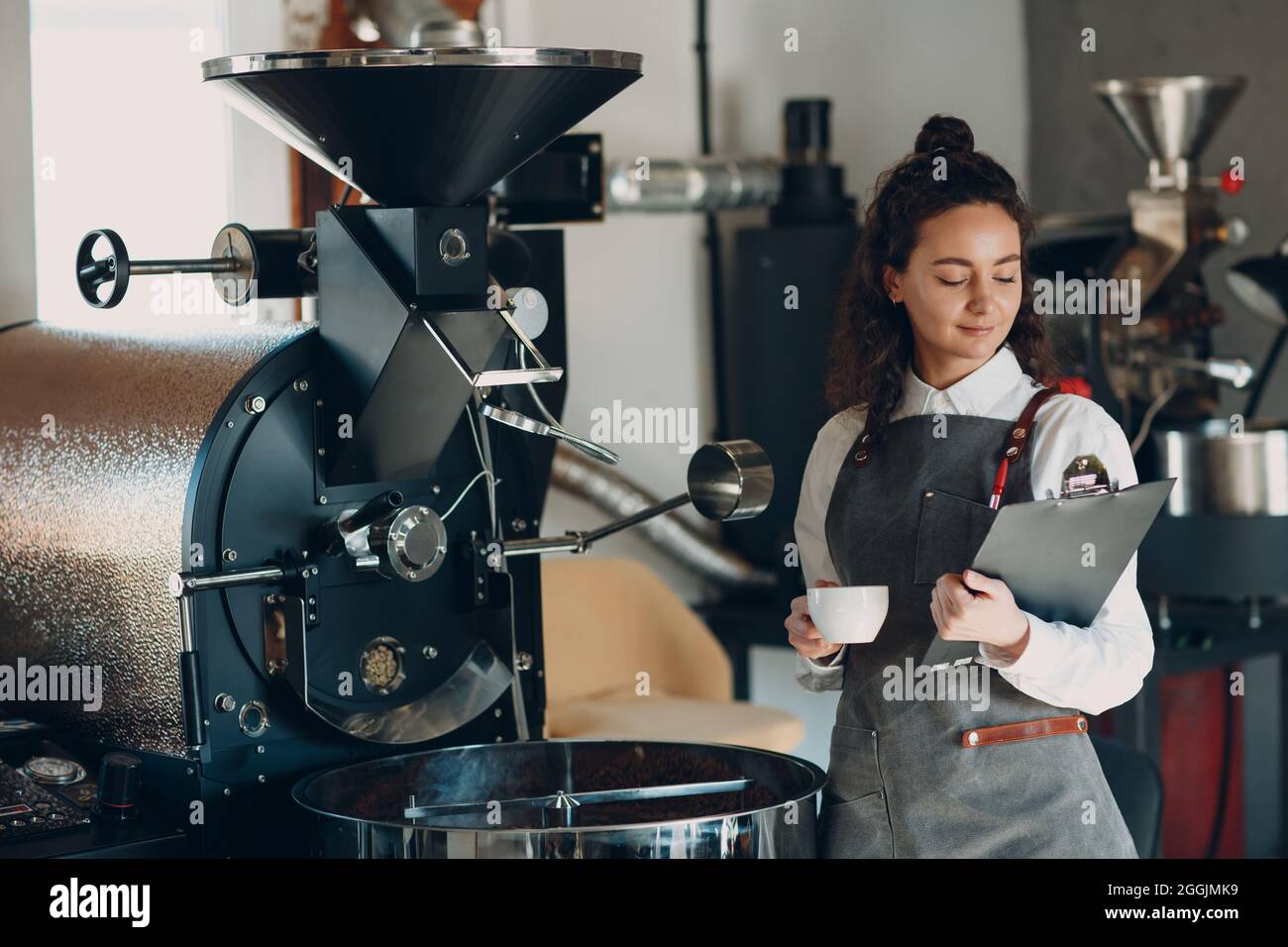 Coffee roaster machine and barista woman with tablet write pen at ...