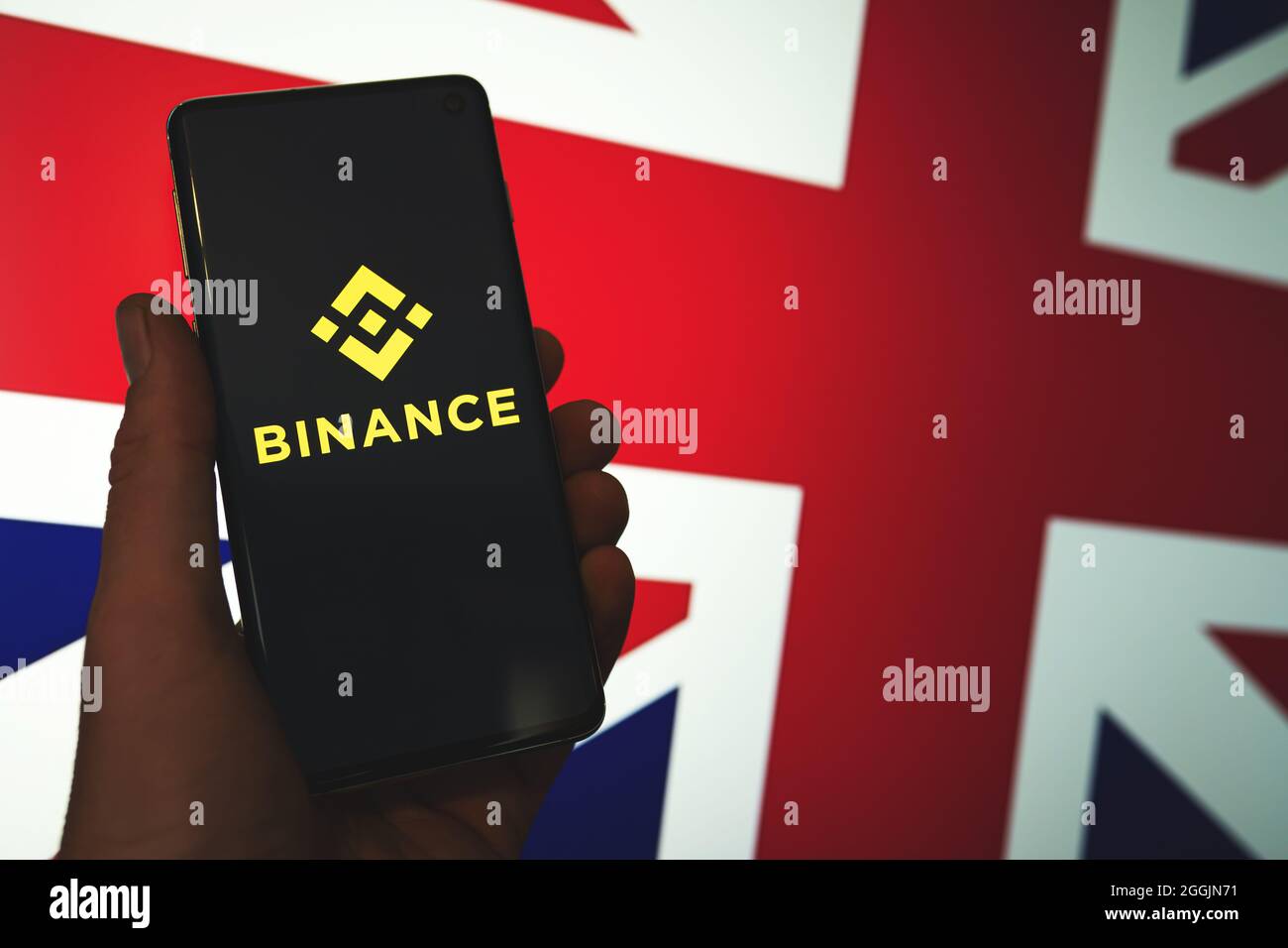 Binance app logo on smartphone in hand with the blurred British Union ...