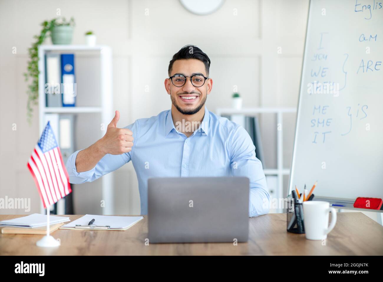 Male foreign languages tutor teaching English online on laptop, showing ...