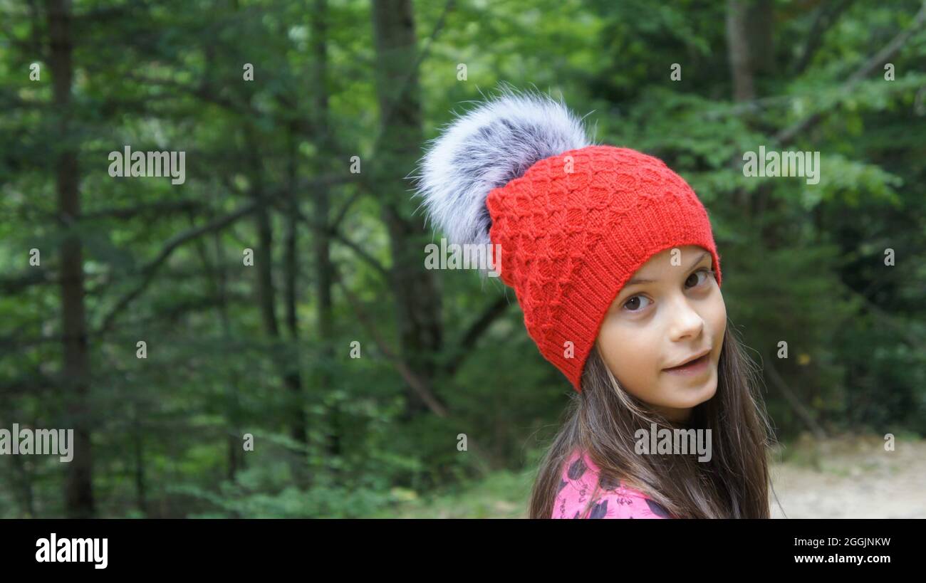 knitted red hat with gray pampon on a girl's model Stock Photo - Alamy