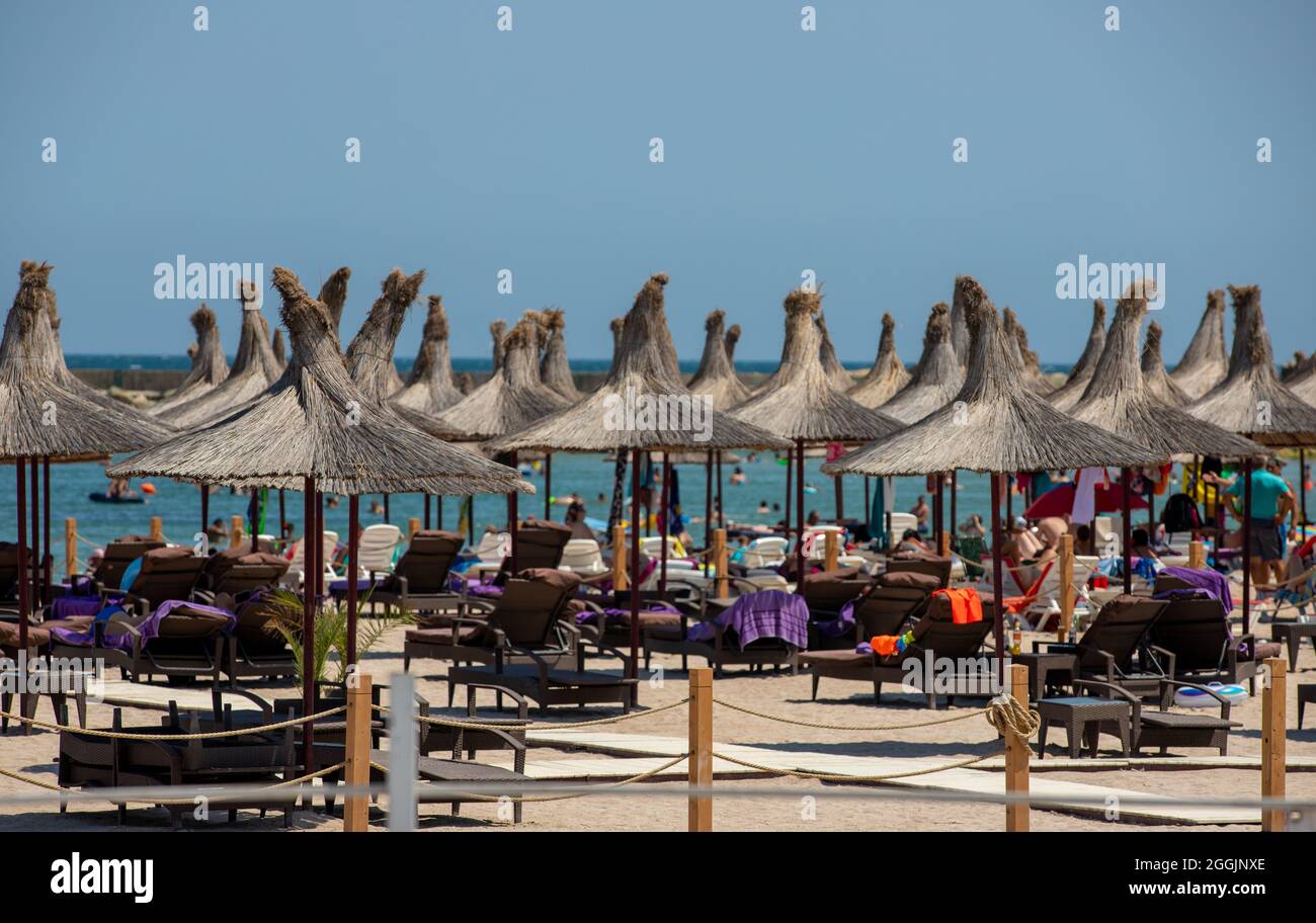 SATURN, ROMANIA - Aug 01, 2021: People resting under solar umbrellas ...