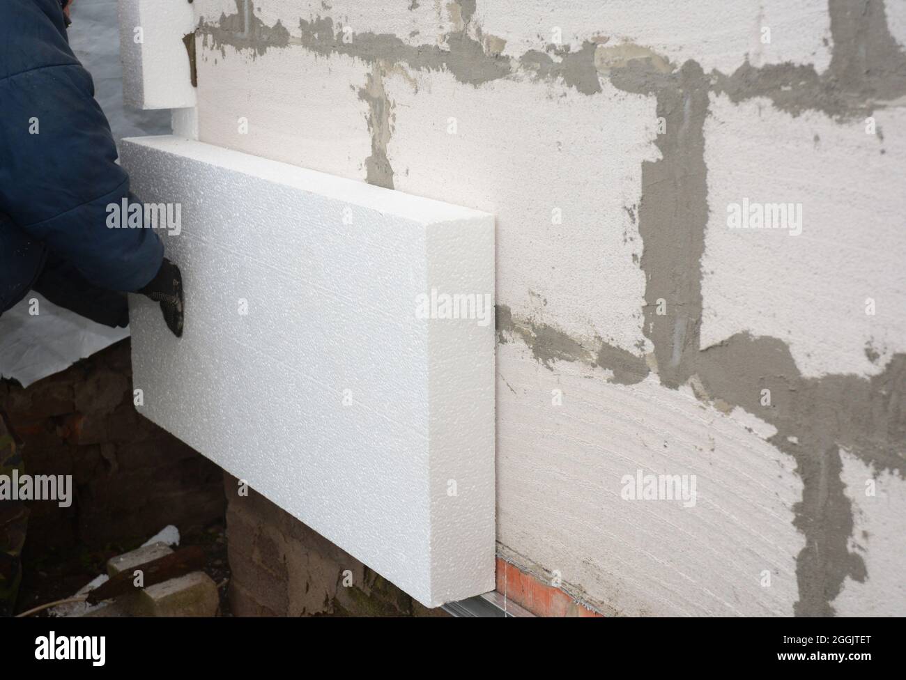 Builder installing rigid styrofoam insulation board for energy saving ...