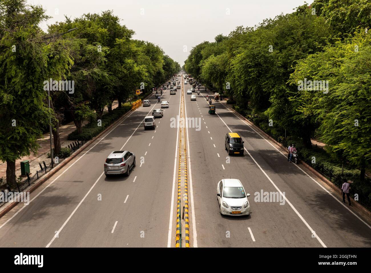 View of a modern wide road in central Delhi with lush green trees on ...