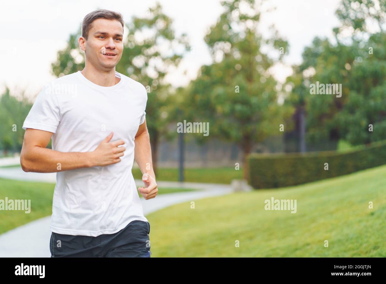 Young sports athlete man in white t-shirt run in the morning in modern ...