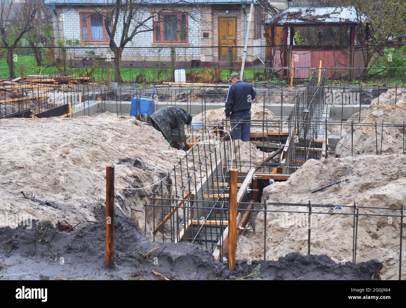Builders pouring a concrete slab formwork along the foundation ...