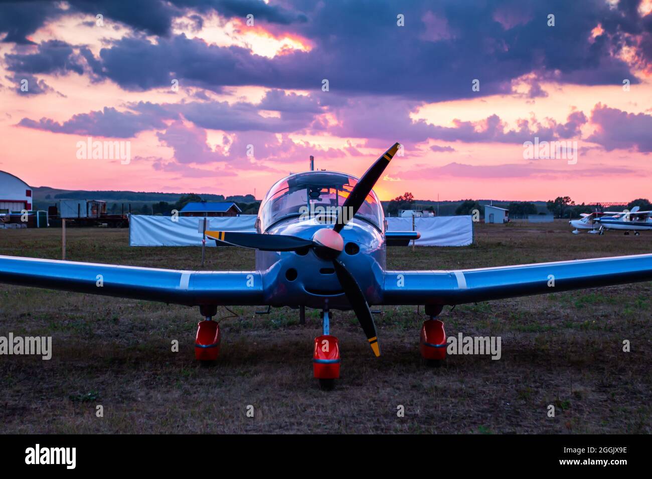 Sports aircraft parked at the airfield at picturesque sunset. Front ...