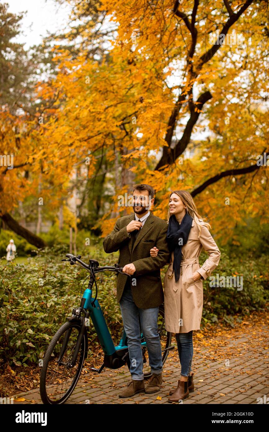 Handsome young couple in the autumn park with electrical bicycle Stock Photo - Alamy