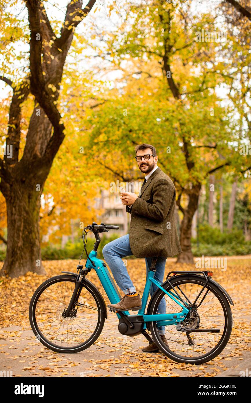 Handsome young man using mobile phone on electric bicycle at the autumn park Stock Photo - Alamy