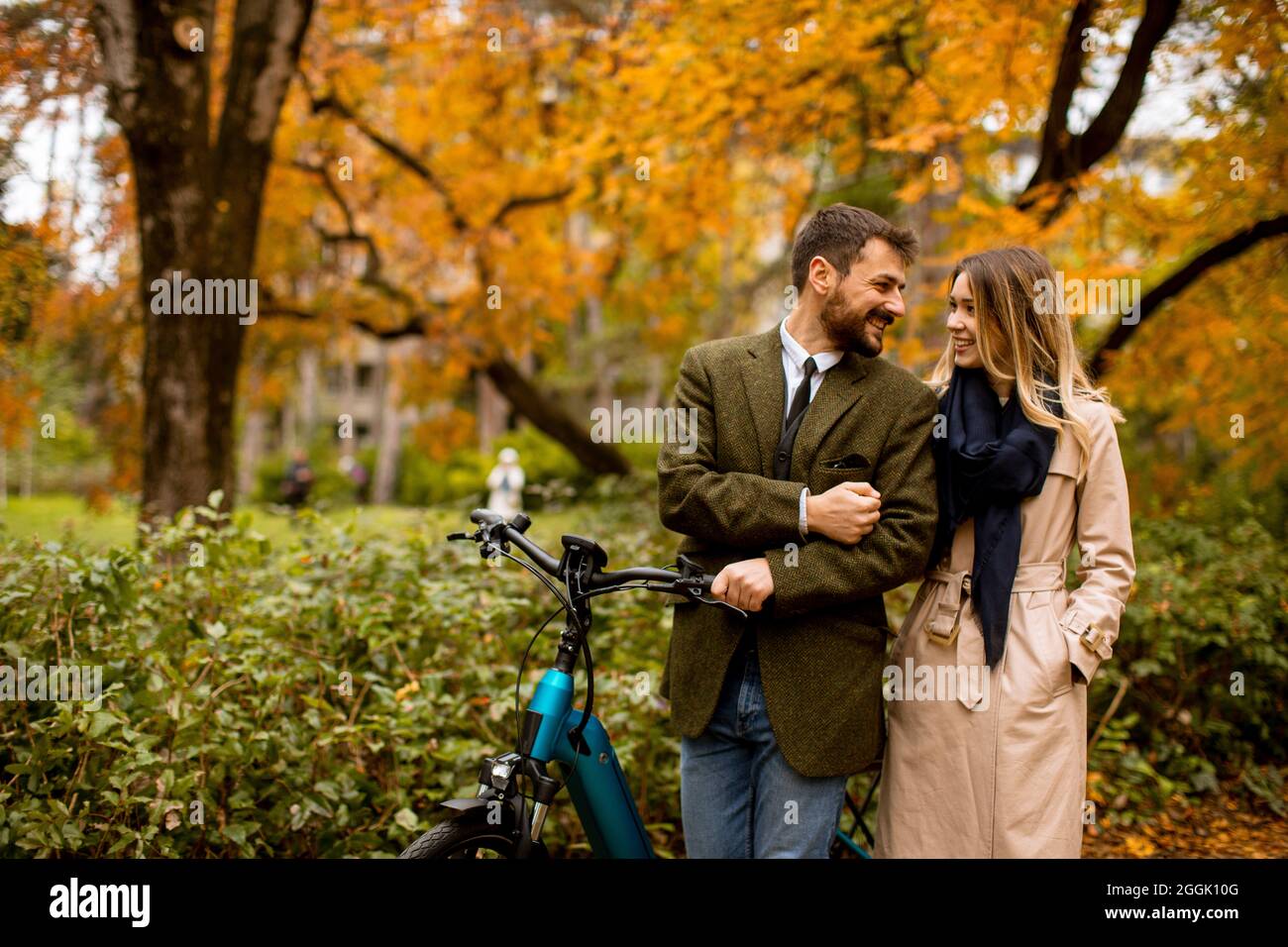Handsome young couple in the autumn park with electrical bicycle Stock Photo - Alamy