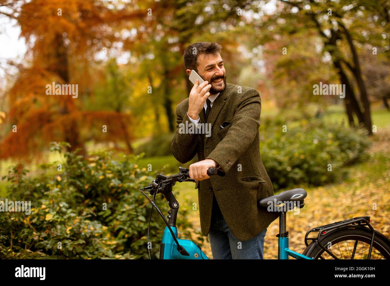 Handsome young man using mobile phone on electric bicycle at the autumn park Stock Photo - Alamy