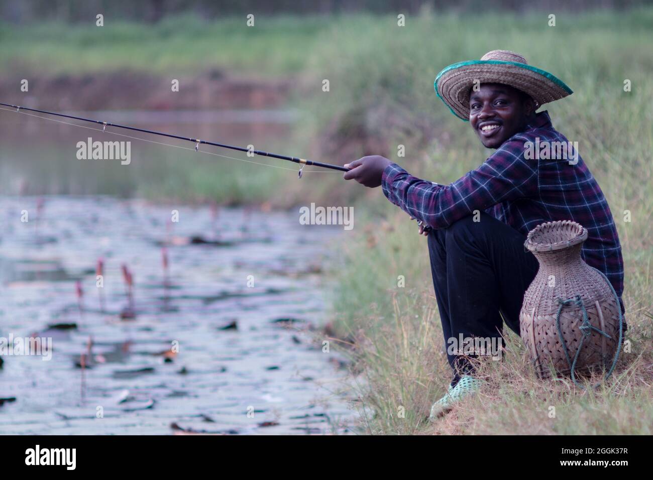 African fisherman happily catches a rod by a pond in a rural area Stock ...
