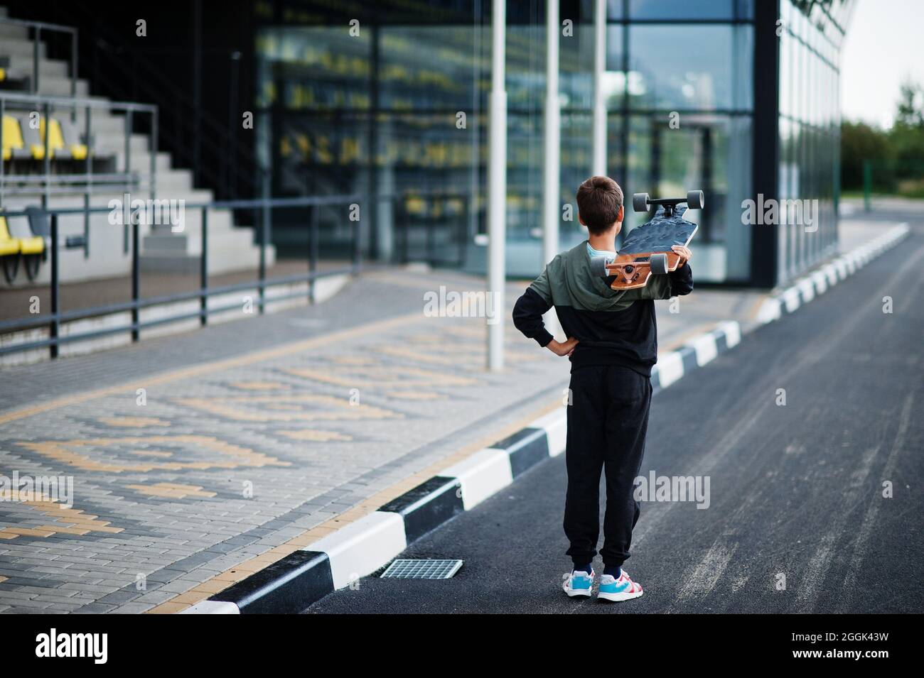 Teenager boy in a sports suit with longboard Stock Photo - Alamy