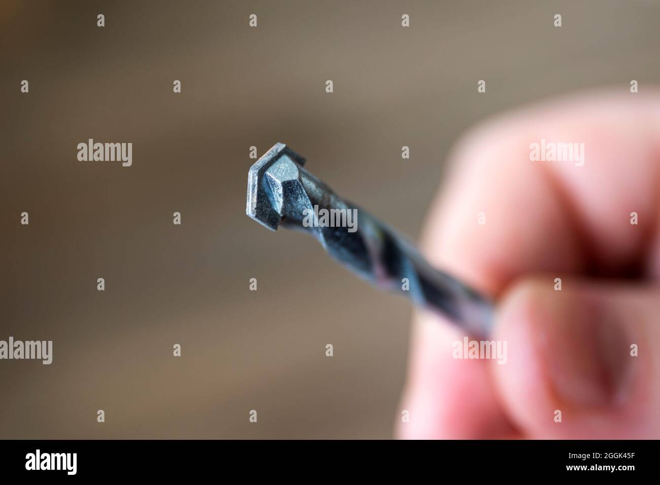 A closeup portrait of a hand of a person holding a stone drill bit. The ...