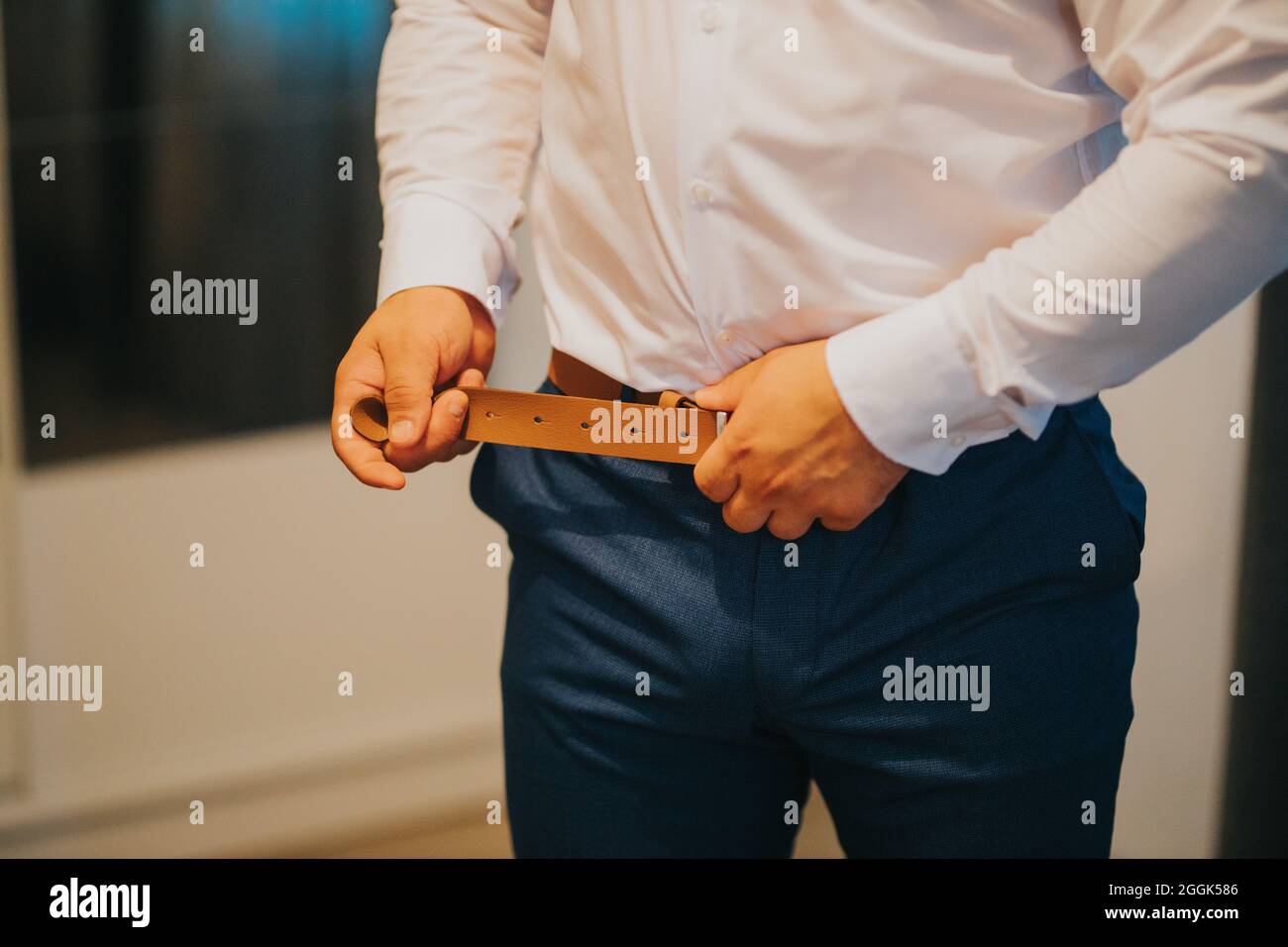 View of a stylish male putting on his belt Stock Photo - Alamy