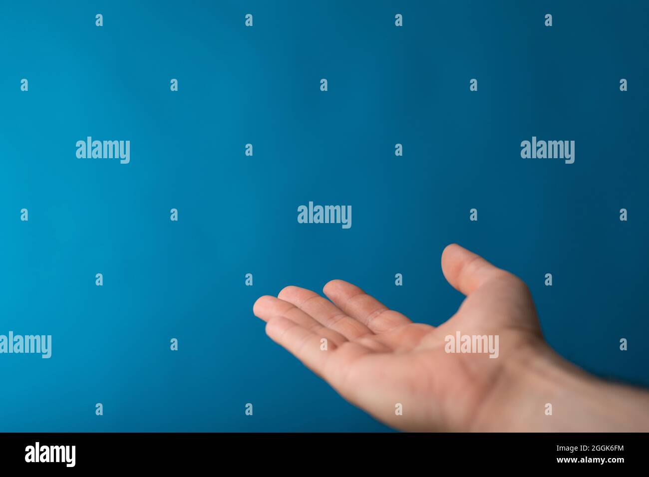 Male showing an outstretched hand with an open palm on a blue ...