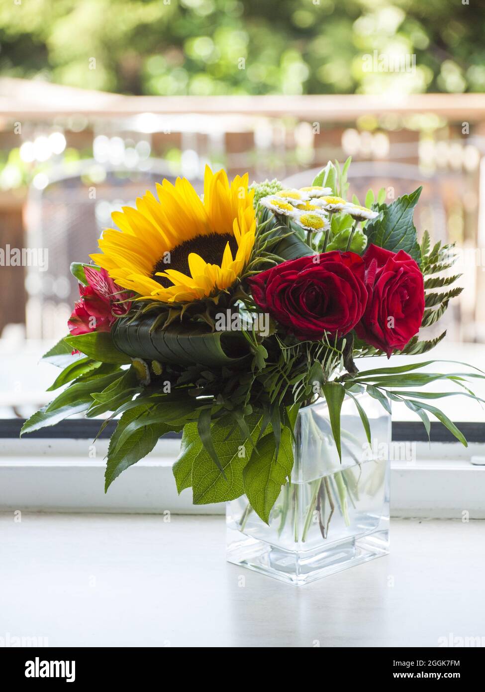 Vertical closeup shot of different flowers in a transparent vase on a ...