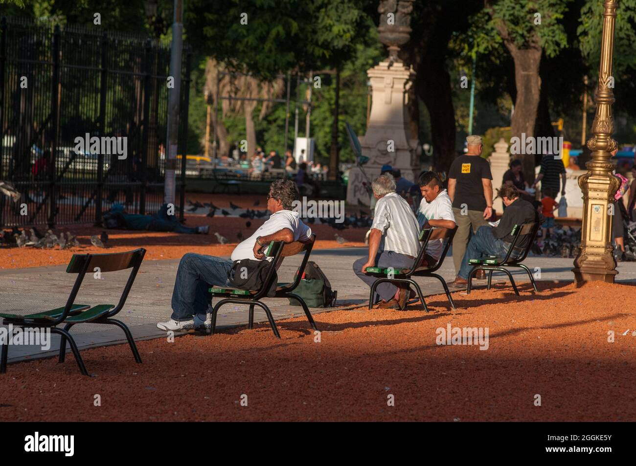 BUENOS AIRES, ARGENTINA - Mar 03, 2021: A group of men relax on benches on a summer afternoon at ...