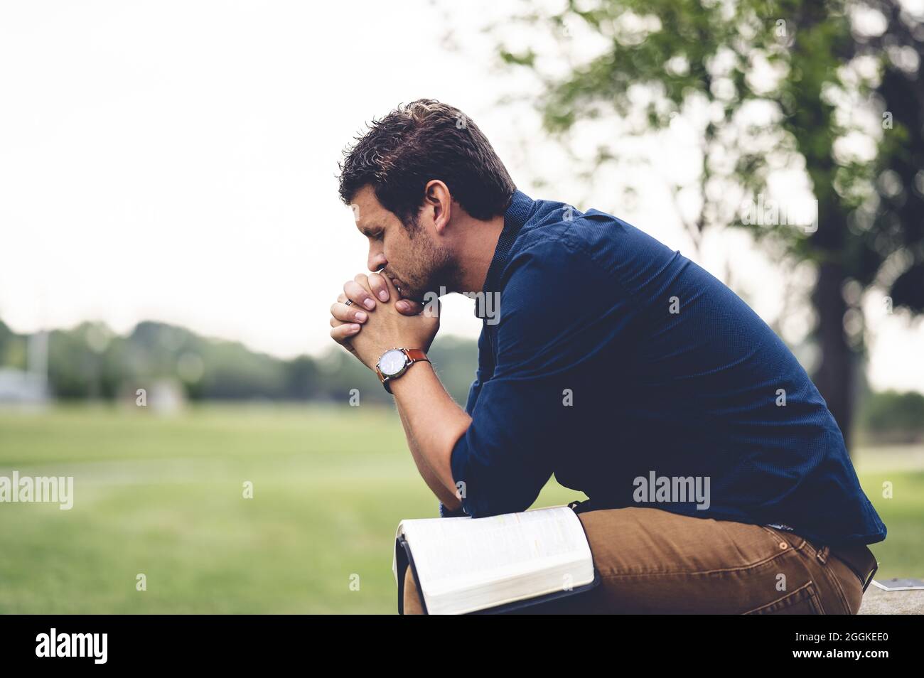 Shallow focus of a male Caucasian praying earnestly at a park in ...