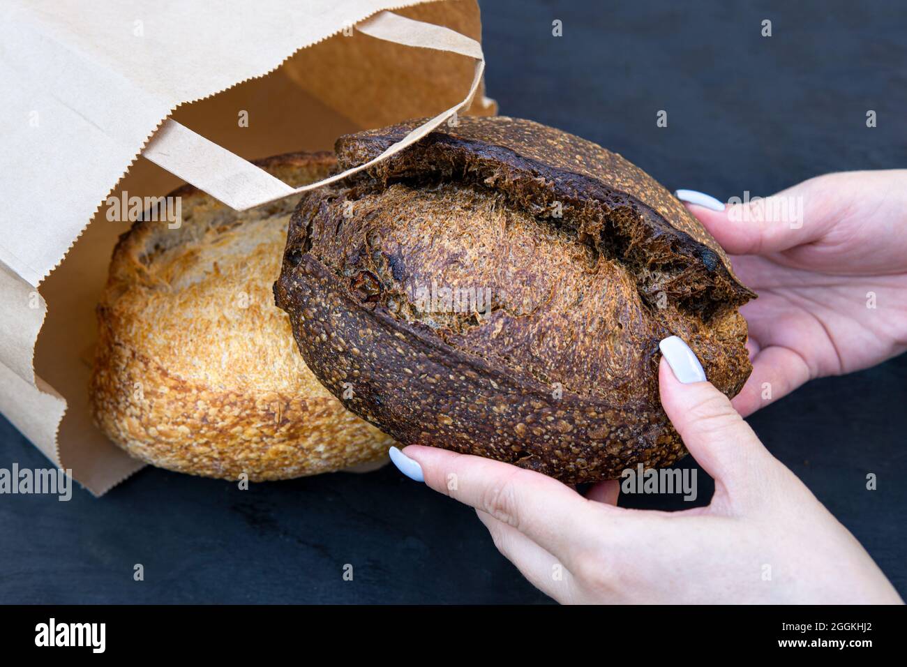 Crop view of female hands packing two freshly baked loaves of bread ...